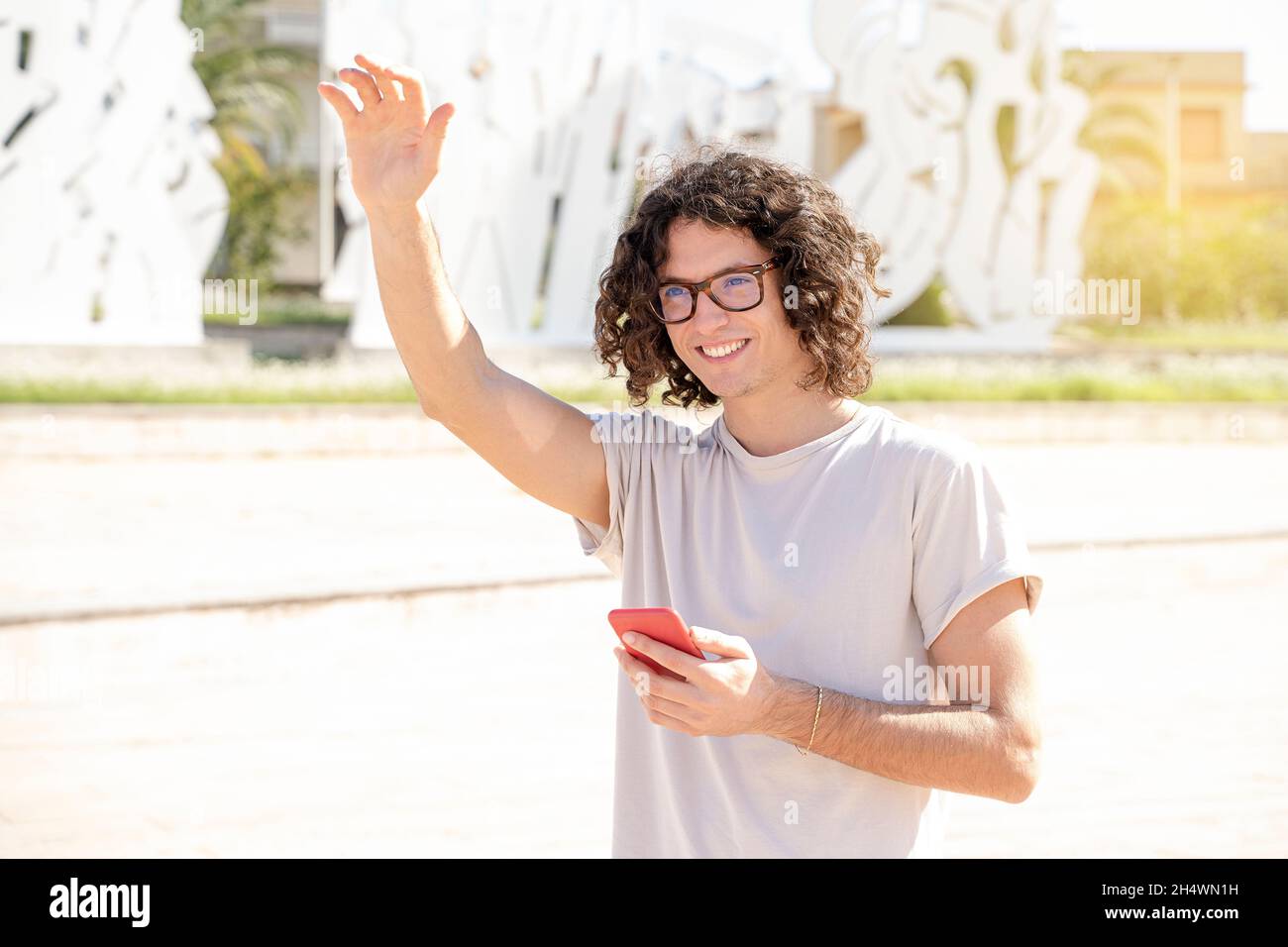 Portrait of happy young italian handsome guy say Hi, holds smartphone ...