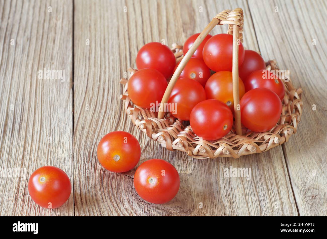 Cherry tomatoes in small wicker basket on wooden background Stock Photo ...