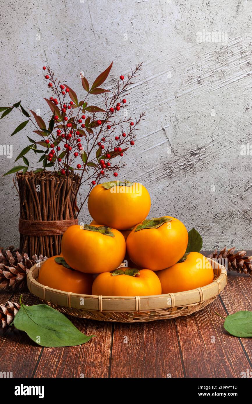 Sweet persimmons in bamboo basket. Persimmon set front view, wooden ...