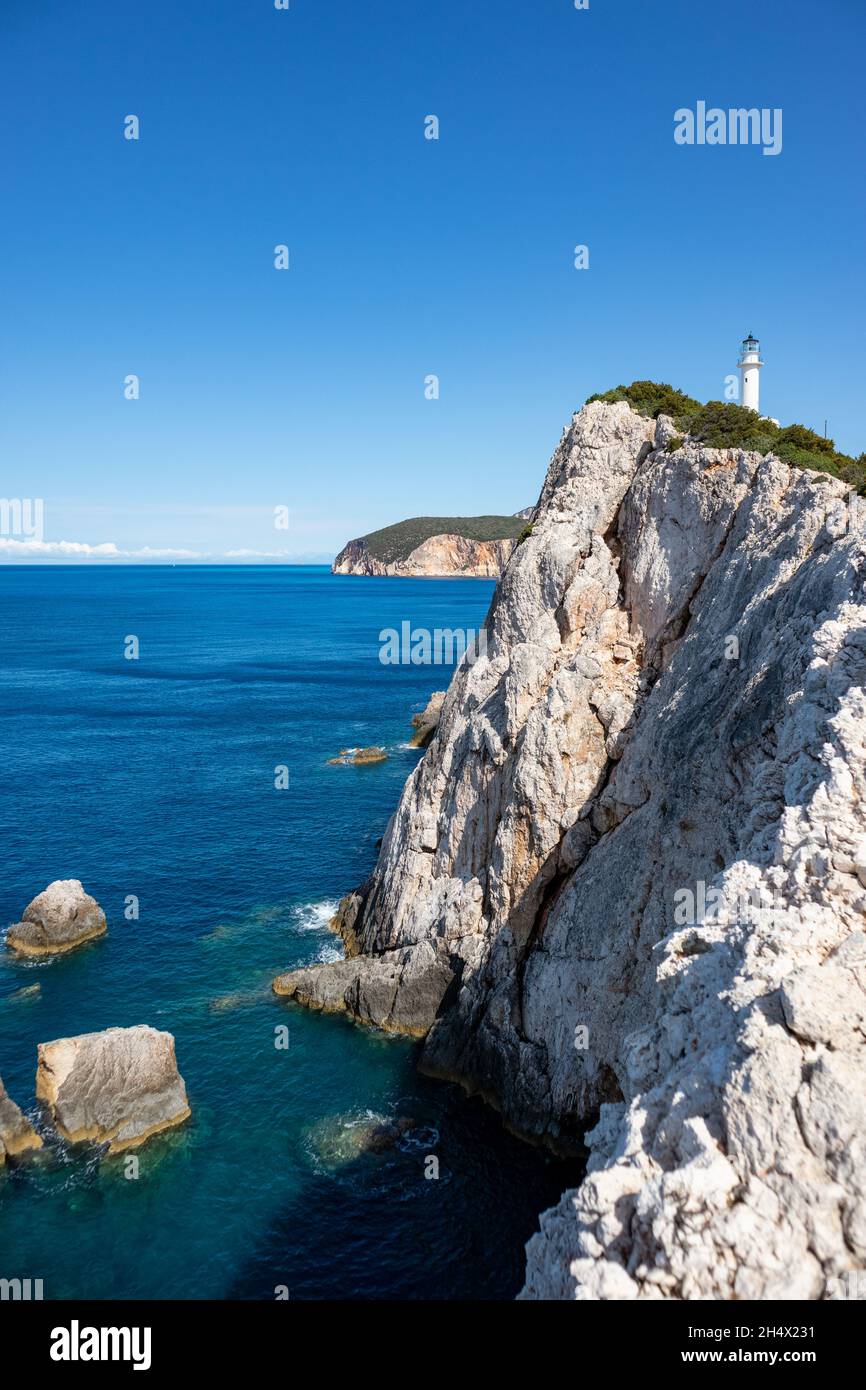 Ionian sea island steep rocky cliff with lighthouse. Bright clear blue ...