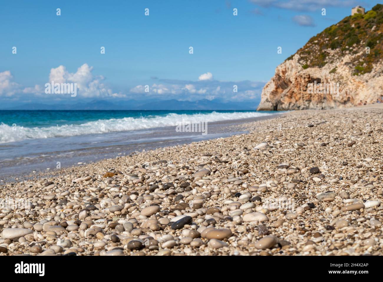 White pebble stones close-up on Mylos beach with azure waves and white ...