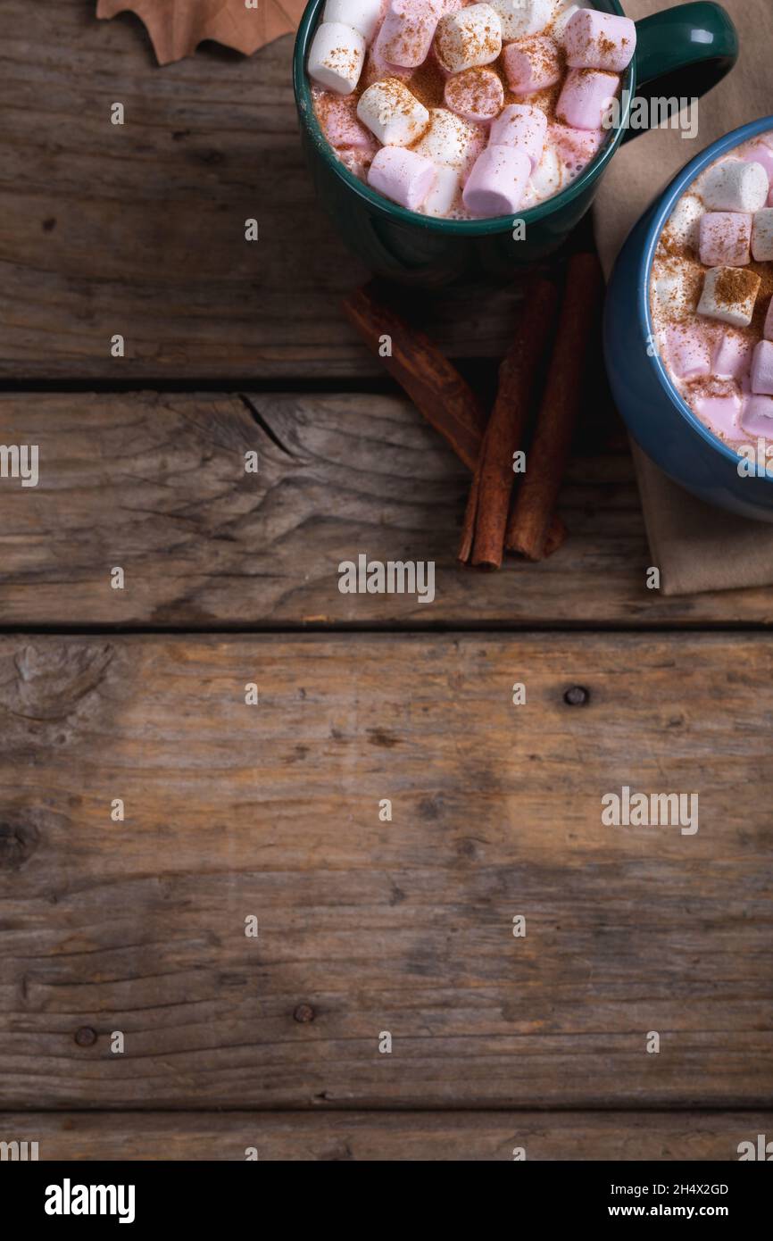 Cinnamon powder sprinkled on white and pink marshmallows in mugs on ...