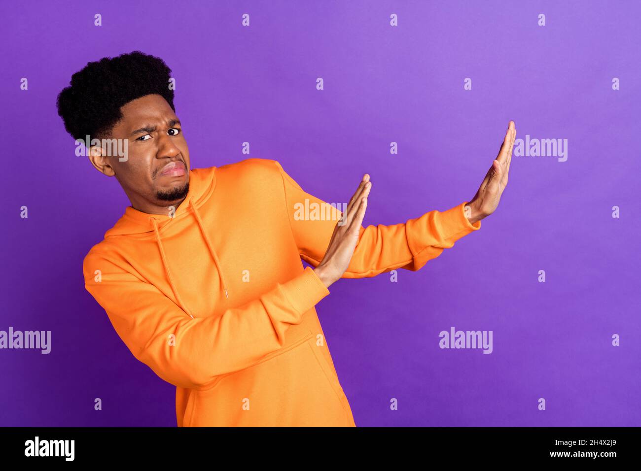 Photo of unhappy brown haired disgusted young dark skin man hold hands ...