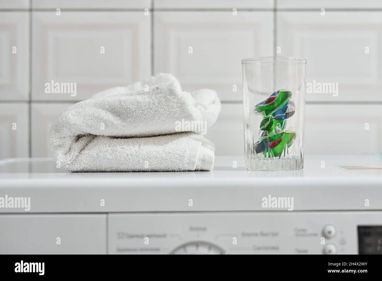 Towel with laundry capsules and detergent on the top of washing machine ...