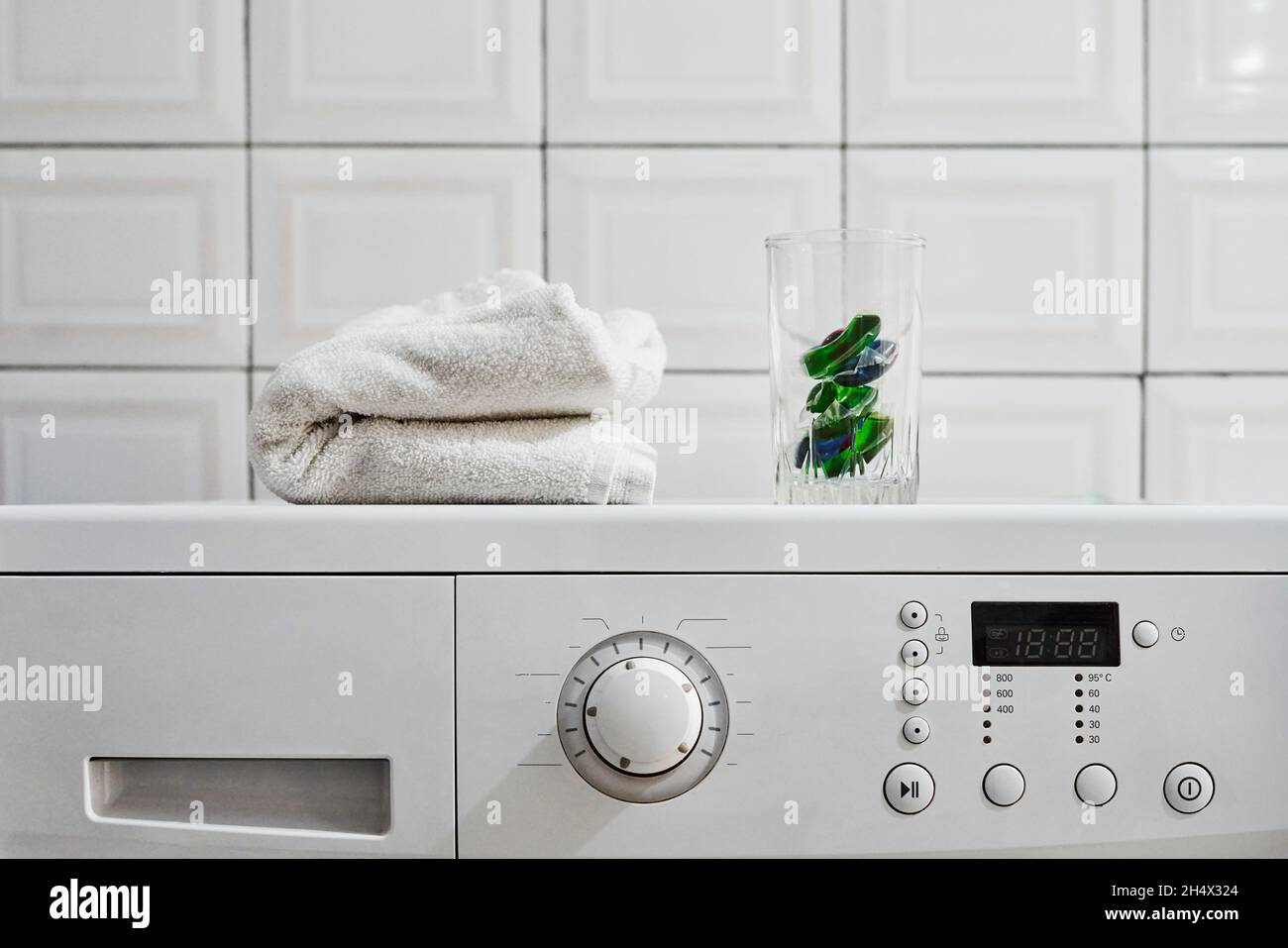Towel with laundry capsules and detergent on the top of washing machine ...
