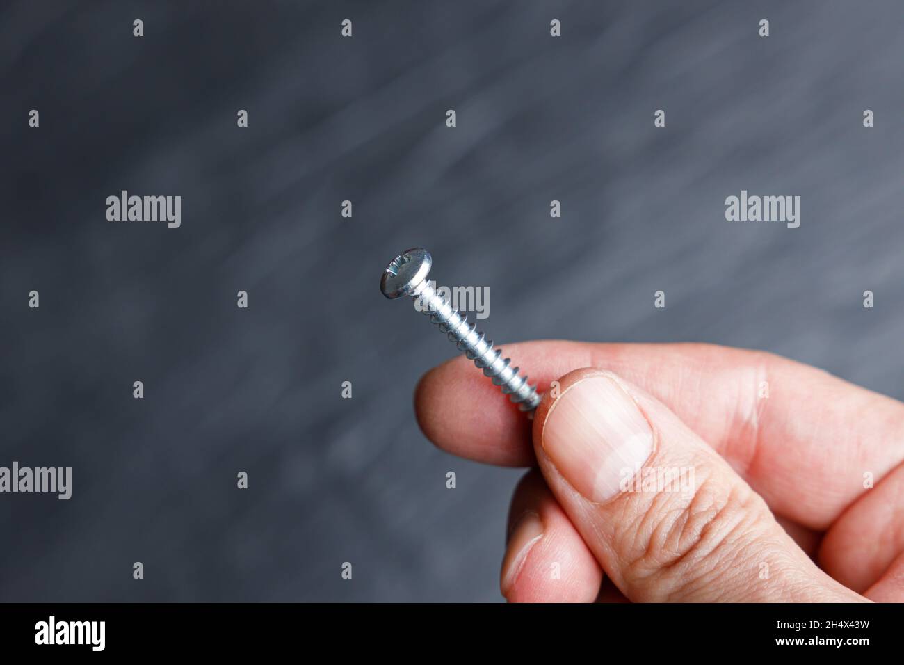 Hand holding steel screw on a black background Stock Photo - Alamy