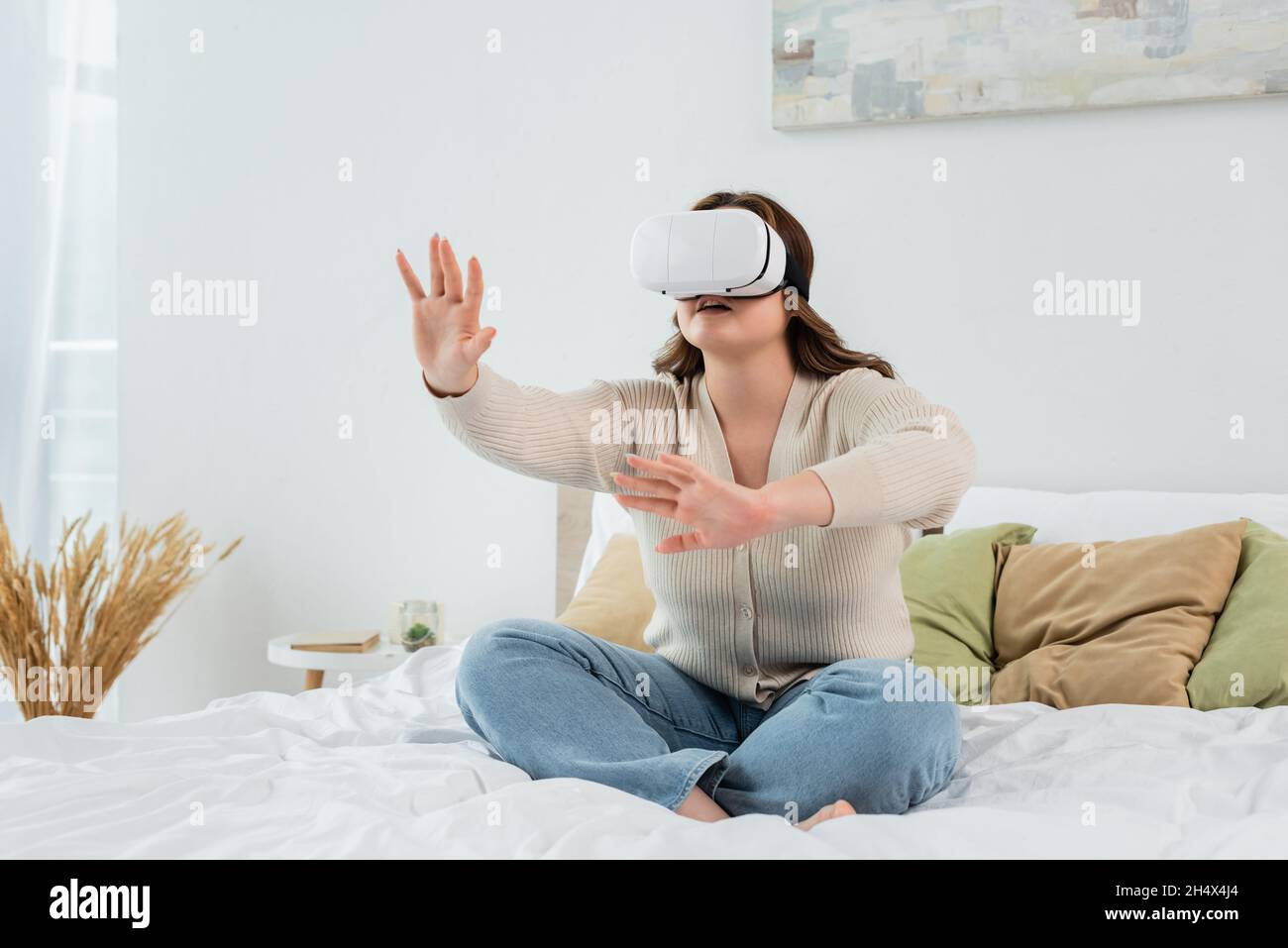 Plus size woman using virtual reality headset on bed Stock Photo - Alamy