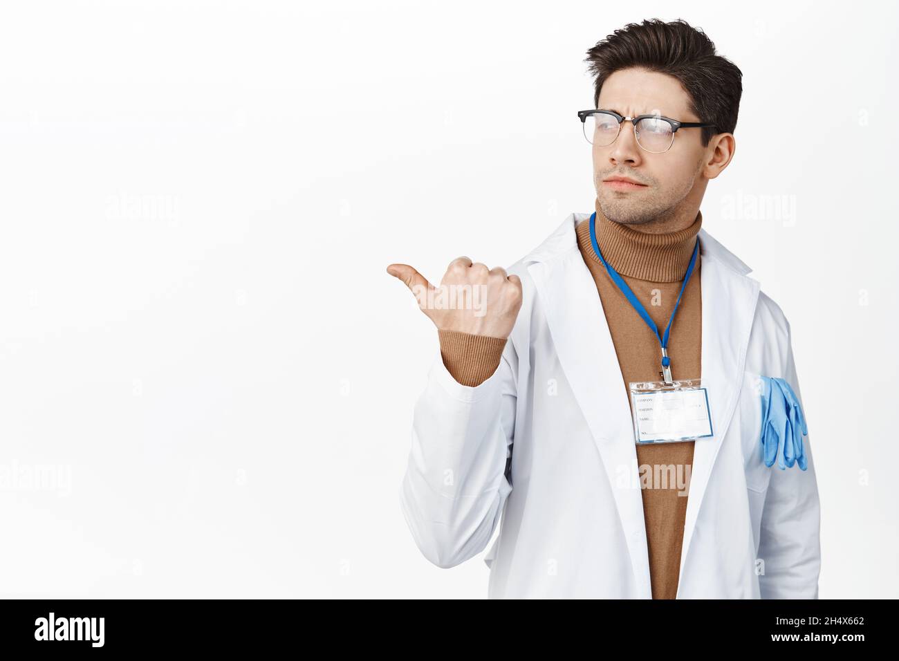 Disappointed doctor in robe with name tag, pointing left and looking ...
