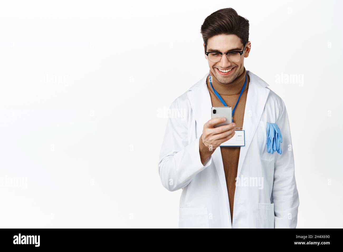 Smiling doctor using mobile phone, looking at screen, checking medical ...