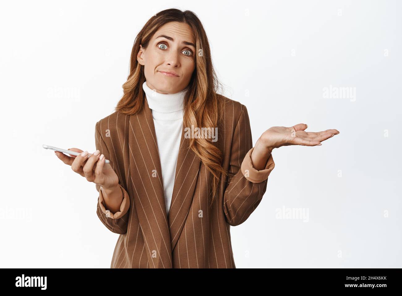 Confused middle aged corporate woman shrugging shoulders, holding ...