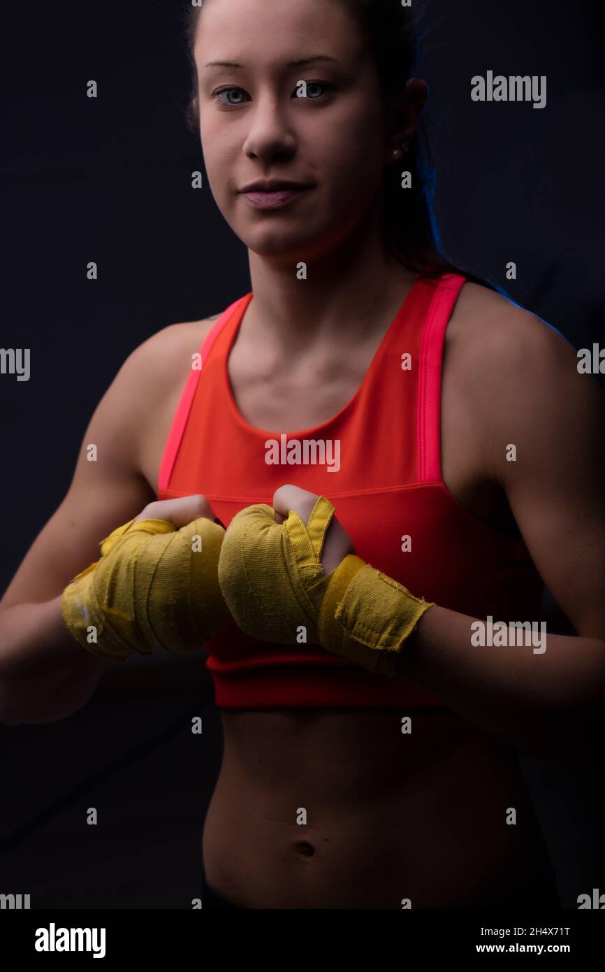 Young and pretty female boxer, wearing red training top and yellow hand ...