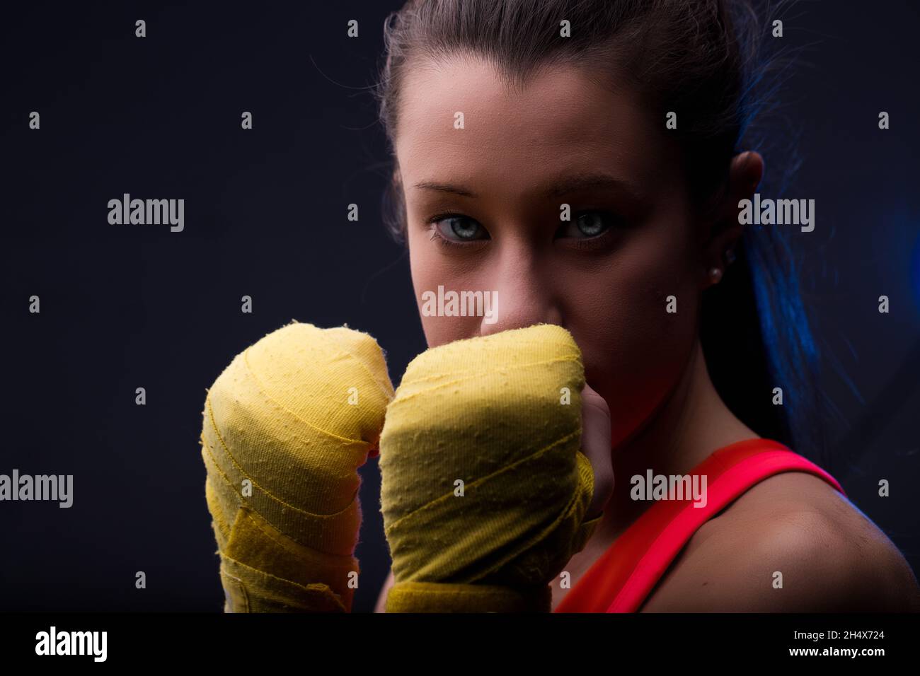 Young woman with expressive look, in yellow boxing handwraps, holding ...