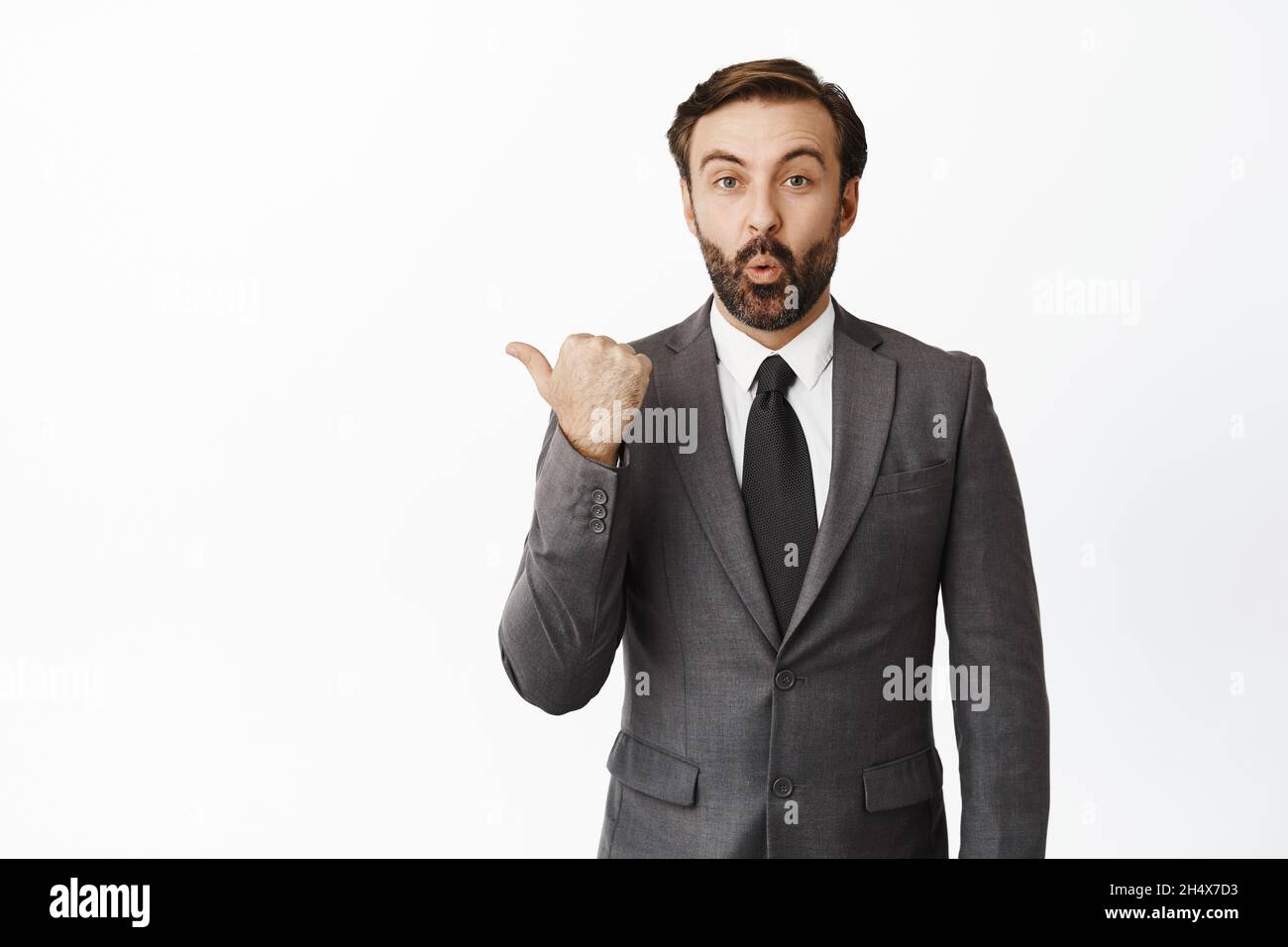 Impressed salesman pointing left, gasping and looking amazed, showing ...