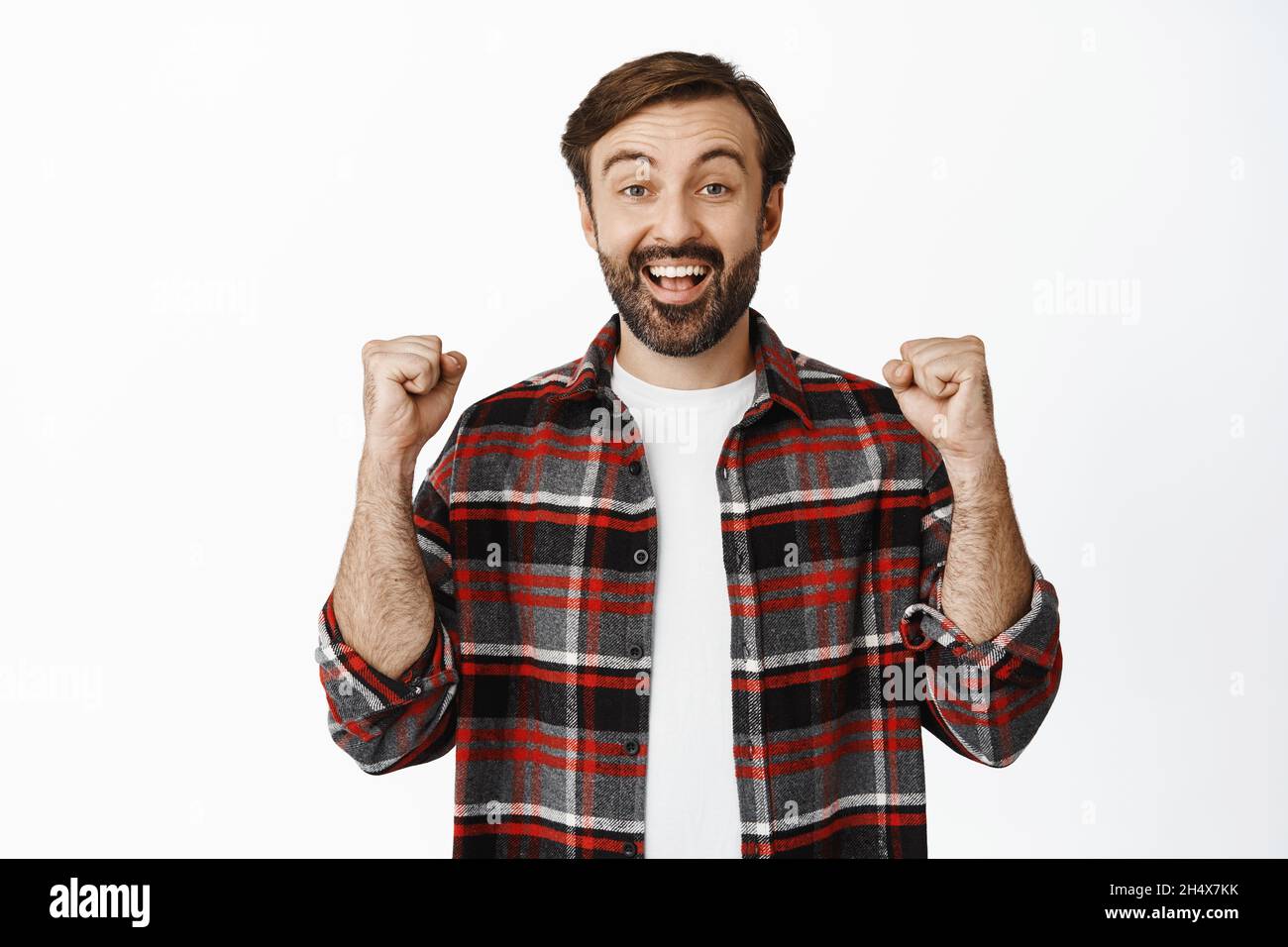 Enthusiastic brunette man with beard, smiling excited, clench fists and ...