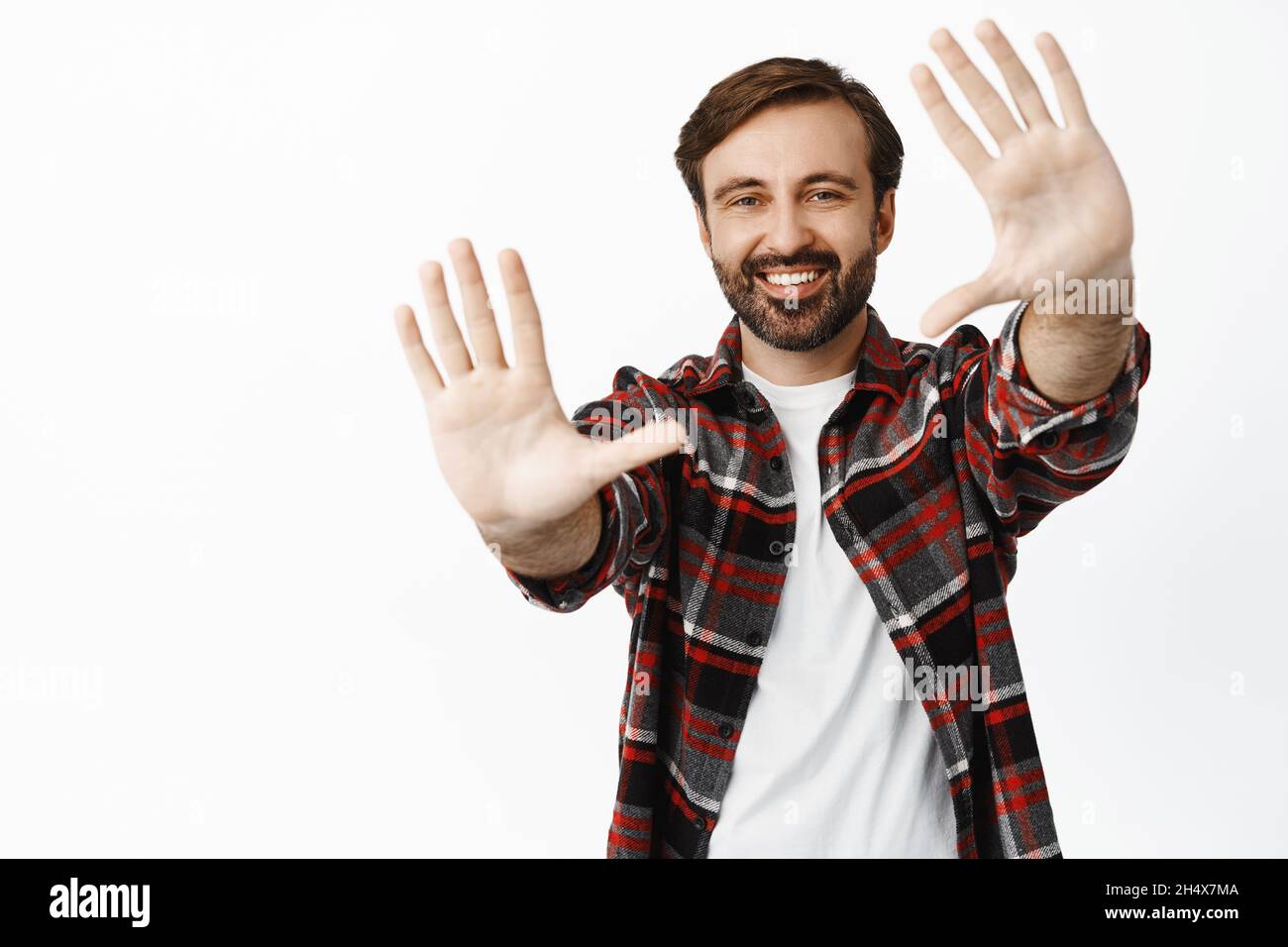 Smiling bearded man stretching out hands, looking through, imaging ...