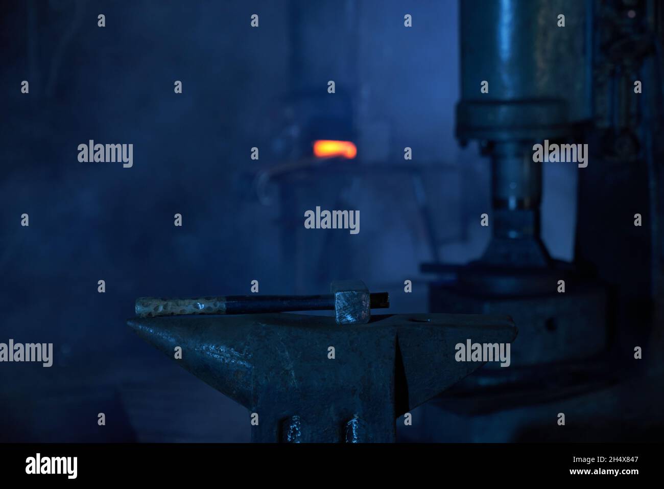 Close up of heavy industrial hammer lying on black anvil with forge ...