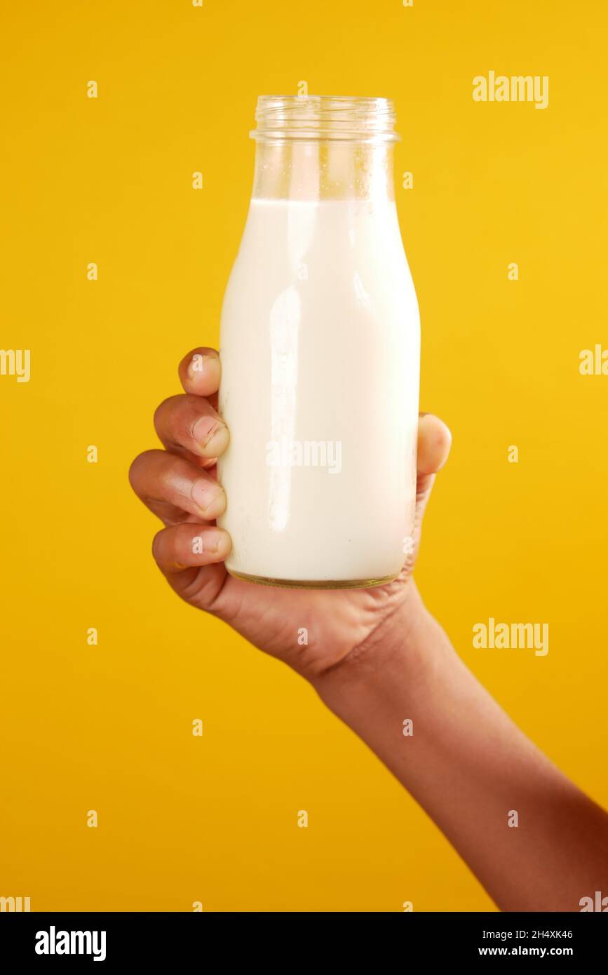 hand hold a milk bottle against yellow background Stock Photo - Alamy