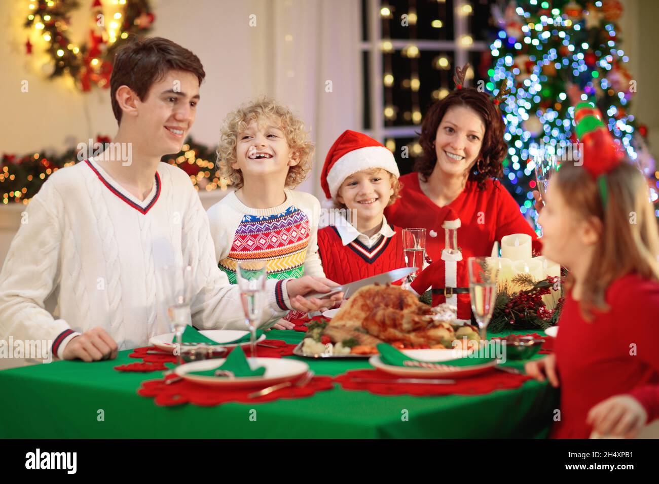 Family with children eating Christmas dinner at fireplace and decorated ...
