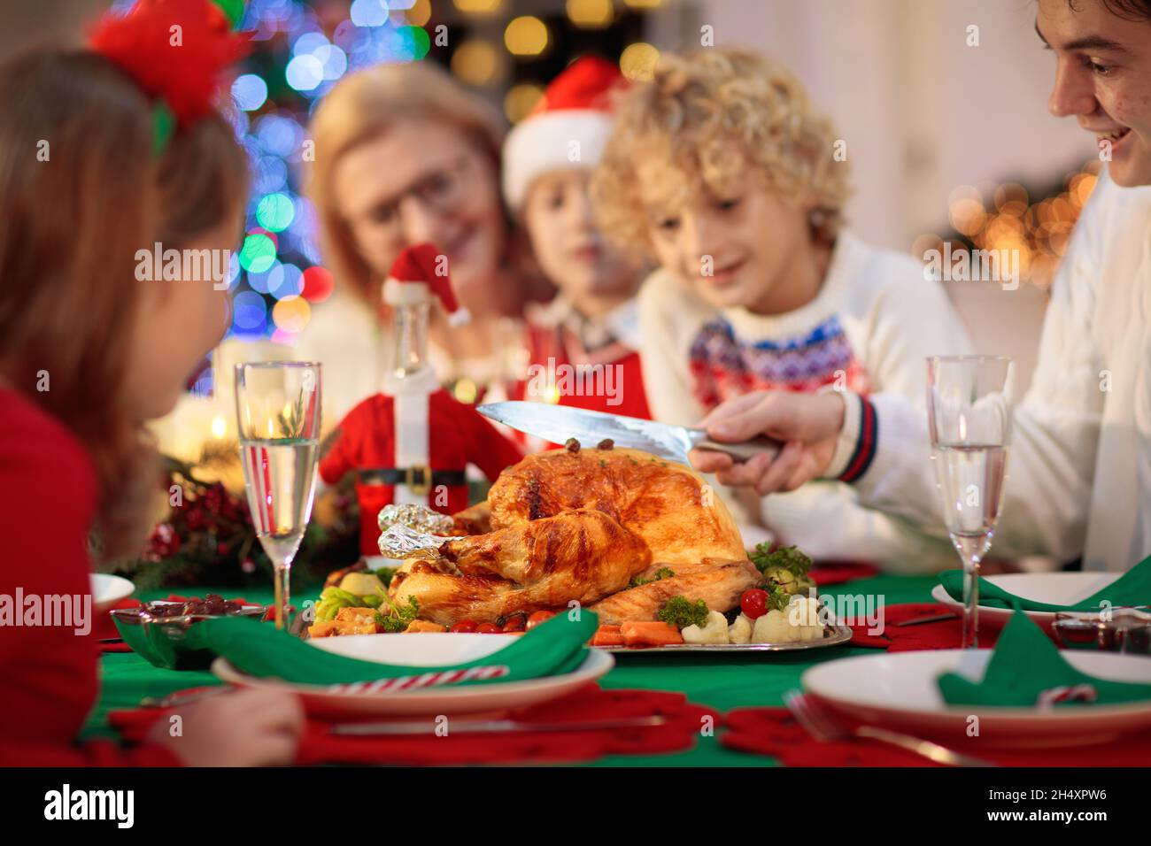 Family with children eating Christmas dinner at fireplace and decorated ...