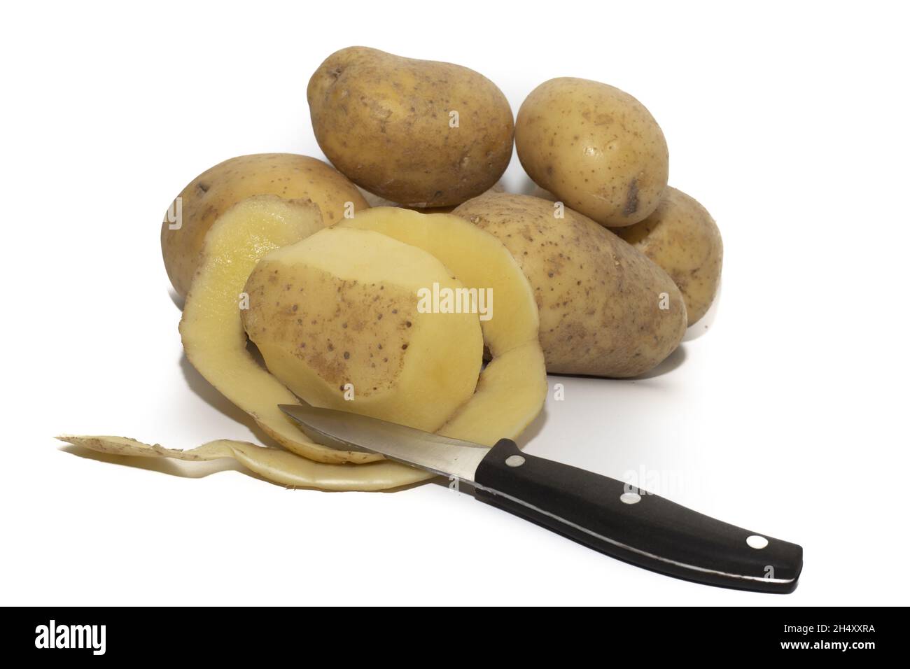 Fresh potatoes with a knife to peel them isolated on a white background ...
