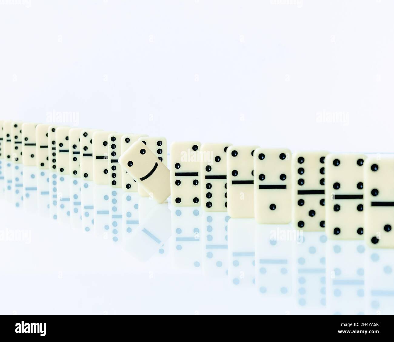 Domino piece stopping domino effect on white background Stock Photo - Alamy