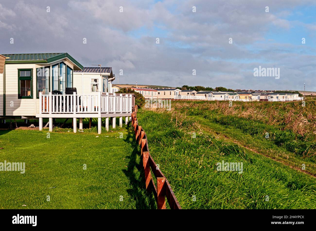 Cream static caravans with and without bold white wooden balconies line ...