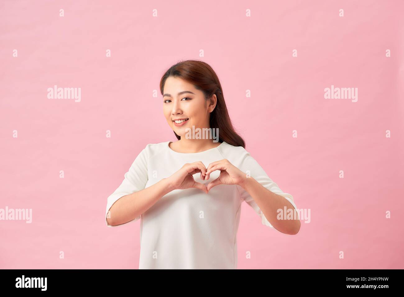 Closeup portrait smiling cheerful happy young woman making heart sign ...