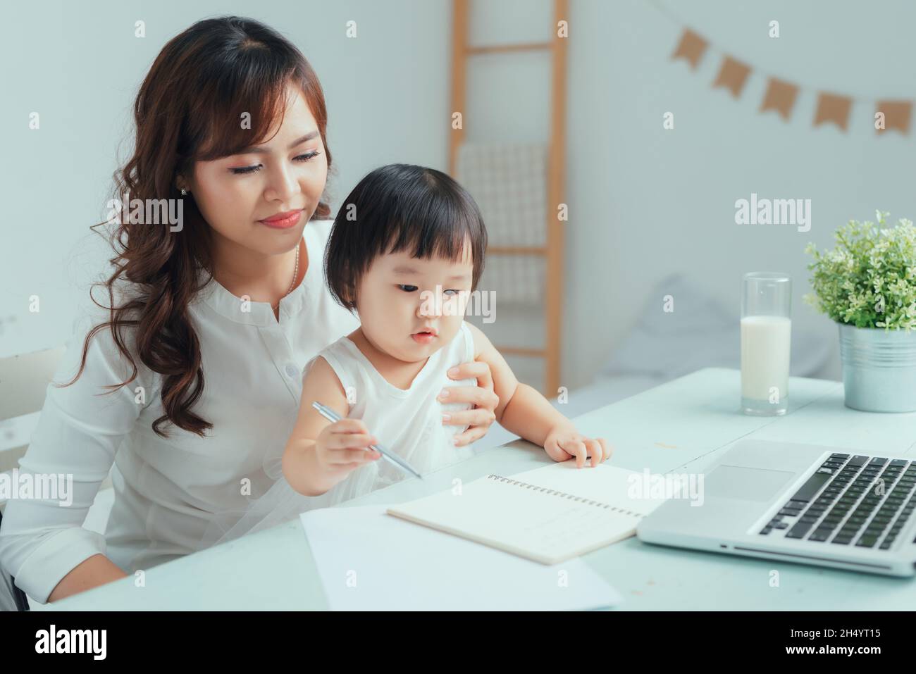 Stay at home mom working remotely on laptop while taking care of her ...