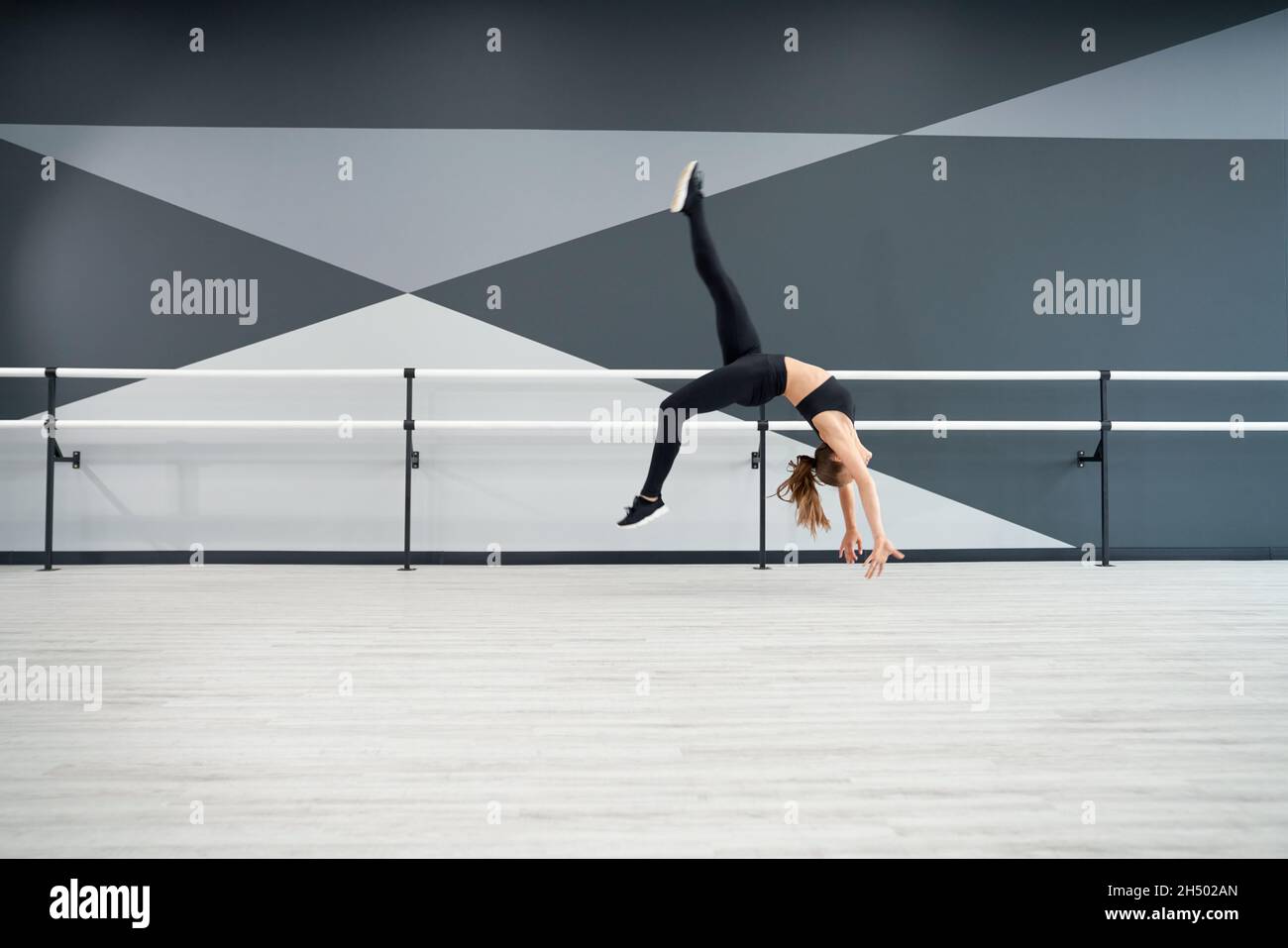 Side view of strong fit woman practicing wheel in jump, doing split in ...