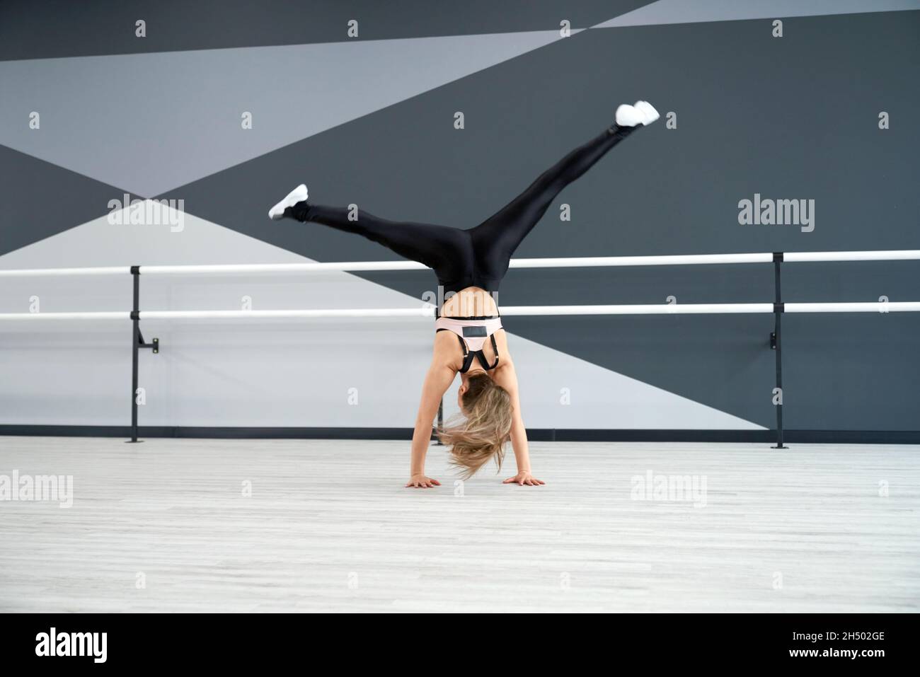 Side view of strong fit woman practicing wheel in jump, doing split in ...