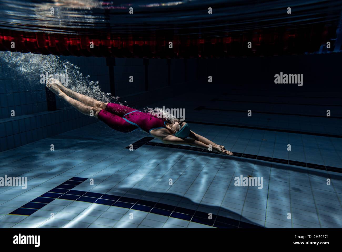 Underwater shooting. One female swimmer training at pool, indoors ...