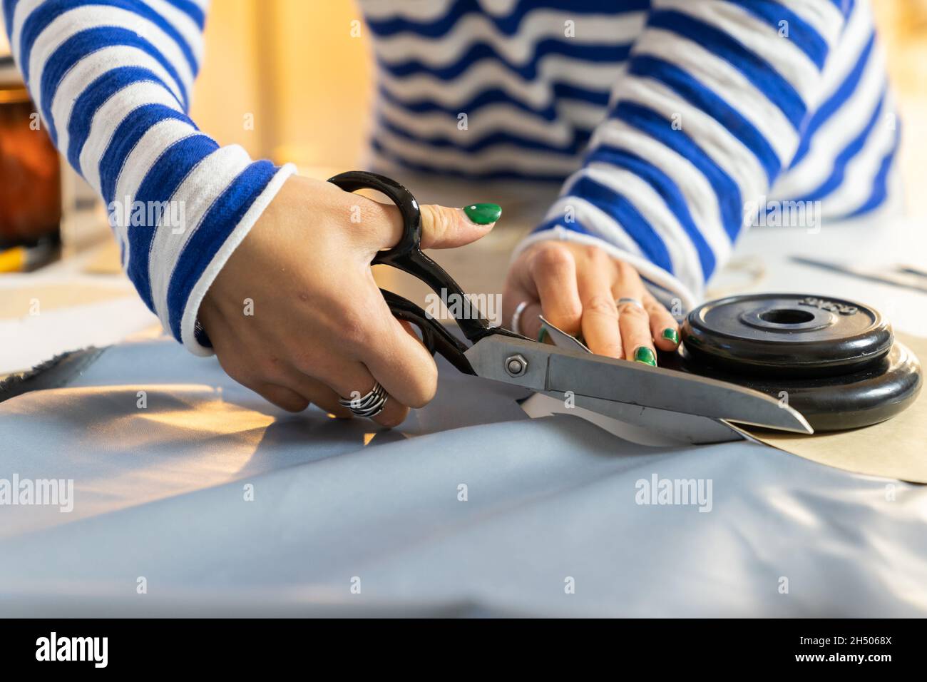 Clothing designer cut fabric using scissors and weights. Sewer working ...