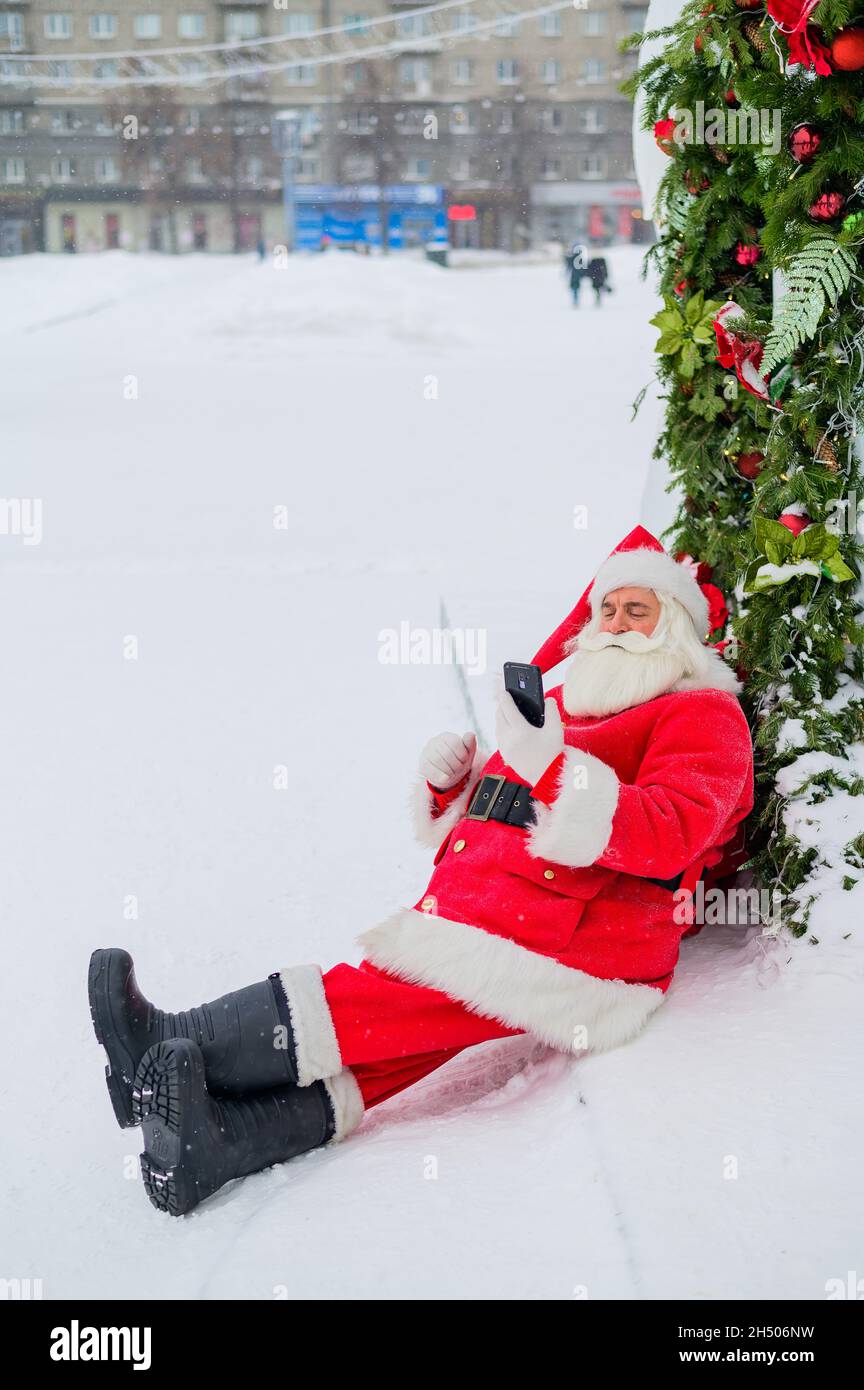 Santa claus using the phone outdoors. Merry Christmas Stock Photo - Alamy
