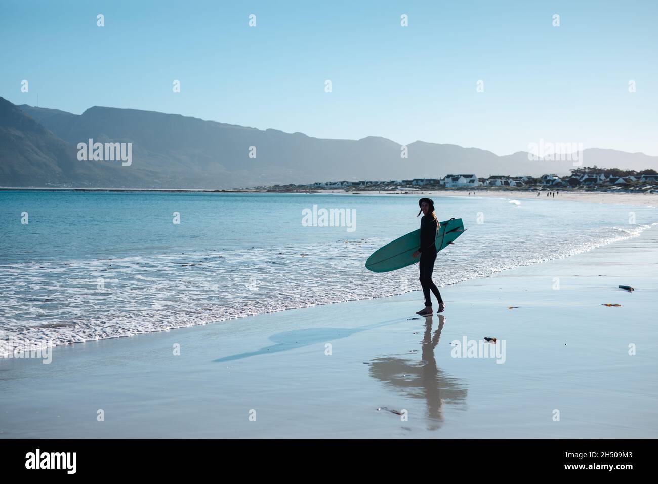 Man carrying surfboard on shore at beach against blue sky with copy ...