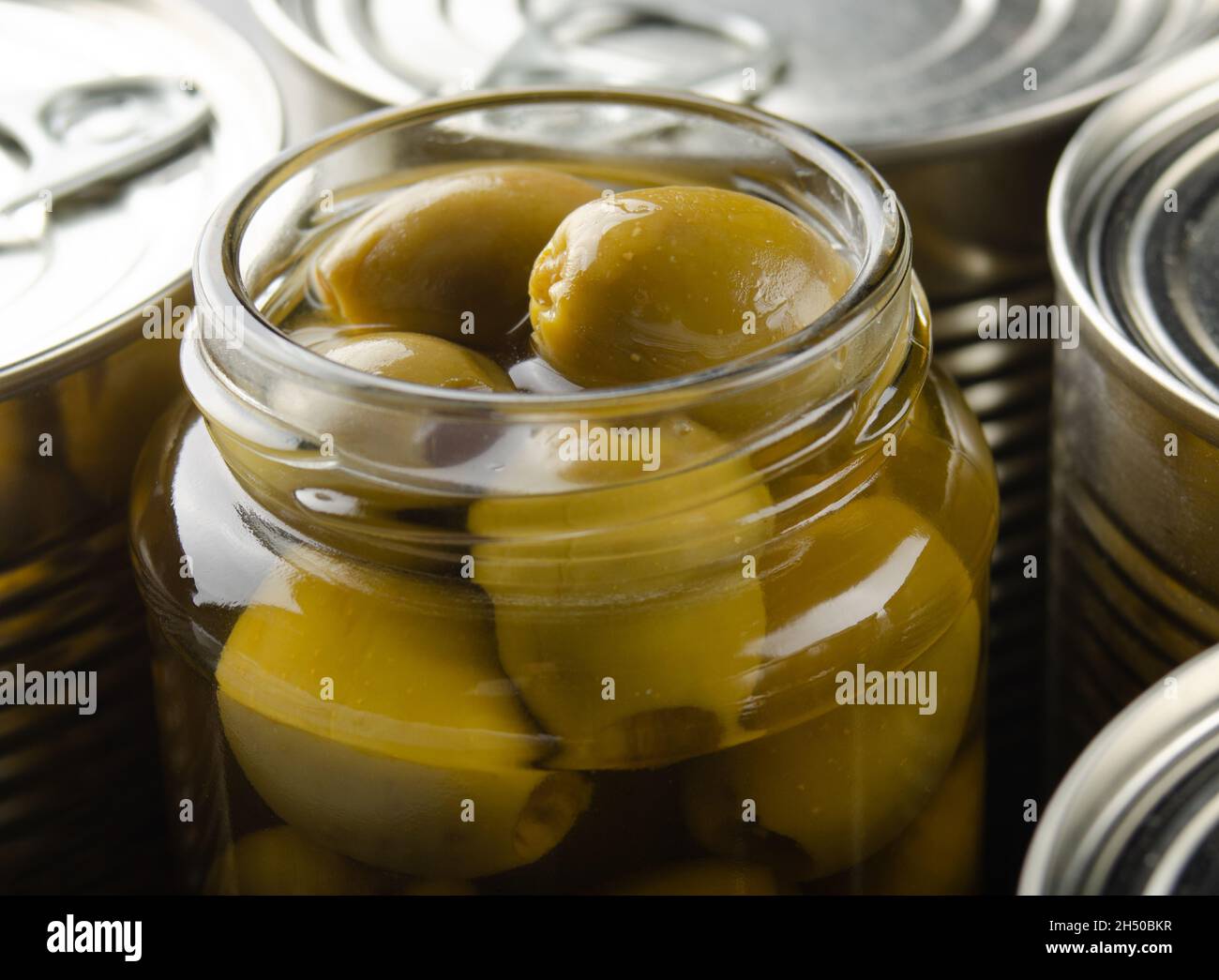 Canned green olives in just opened glass mason jar. Non-perishable food ...