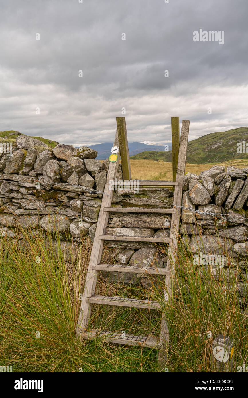 A wooden steps over a wall on a footpath in the hills behind Harlech ...