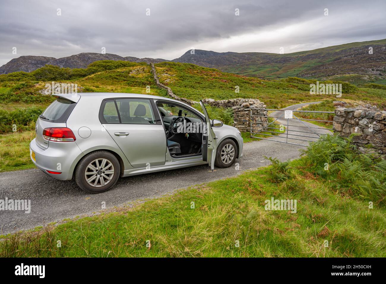 Car waiting for a gate to be opened on a gated road in the hills of ...