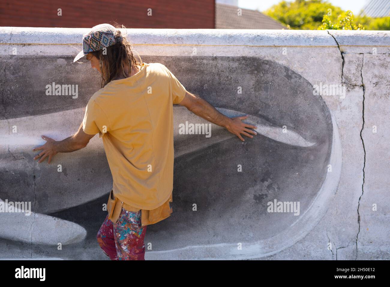 Rear view of male artist walking while touching whale mural painting on ...