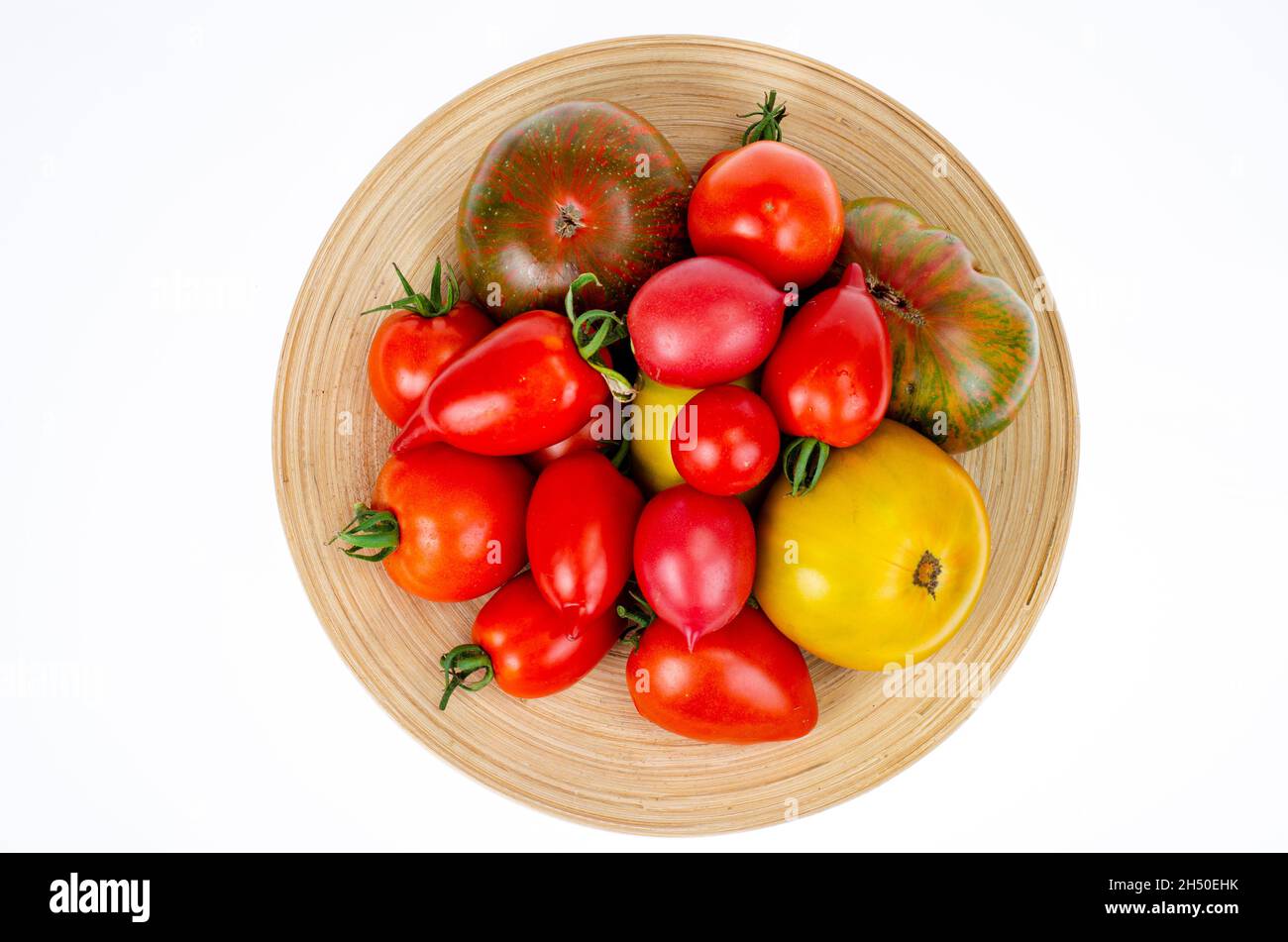 Assorted homemade colorful tomatoes different shapes on wooden plate ...