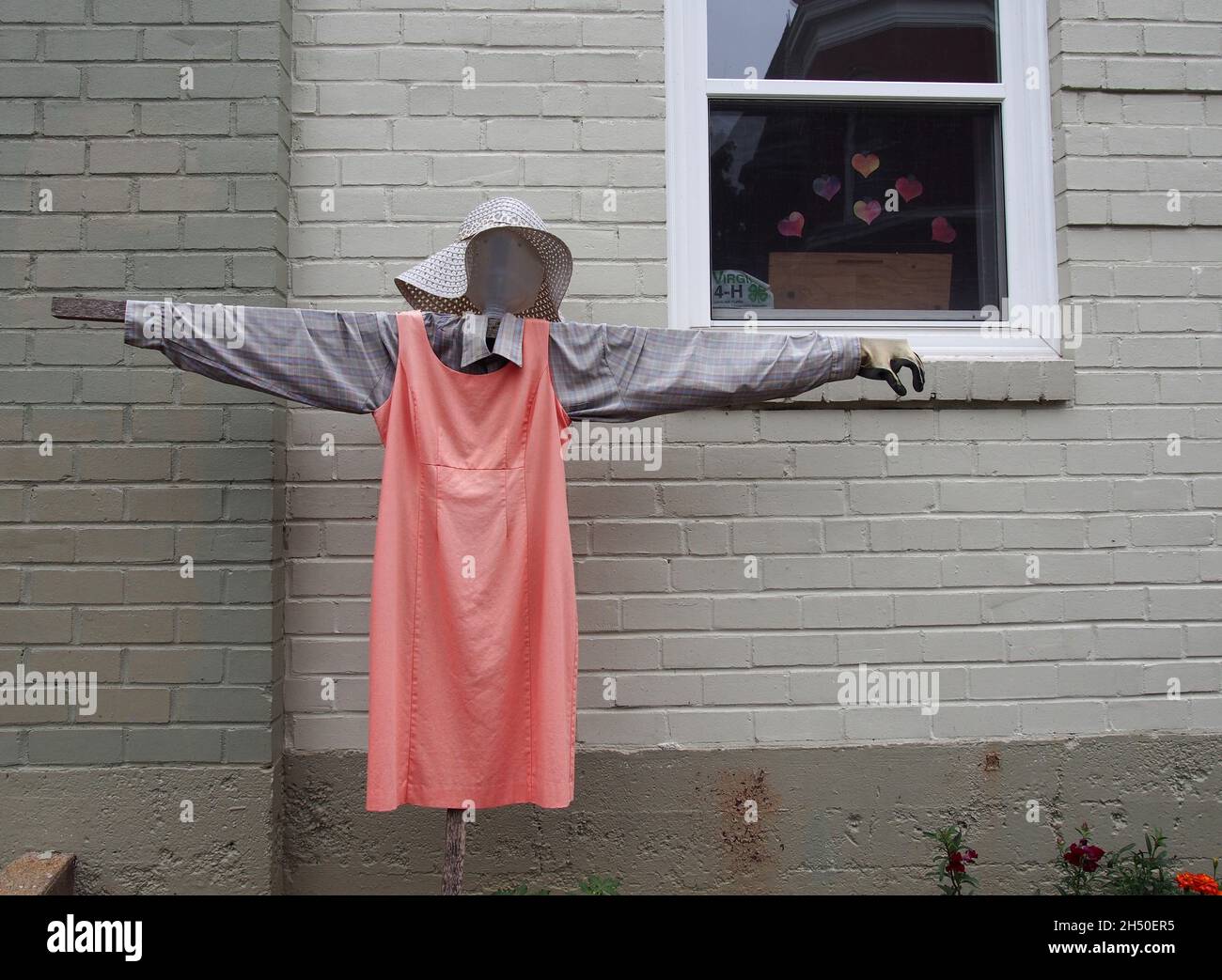 A scarecrow decoration in front of a painted brick wall and window, USA ...