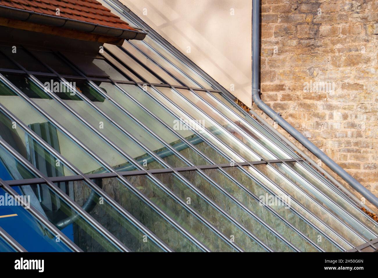 Glass roof reflecting a natural stone wall Stock Photo - Alamy
