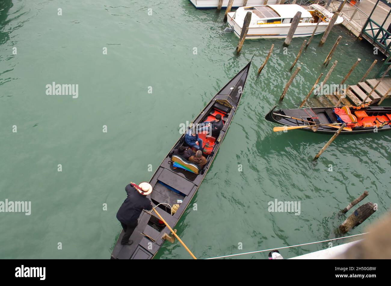 A Gondolier steering a Gondola among other boats including the river ...