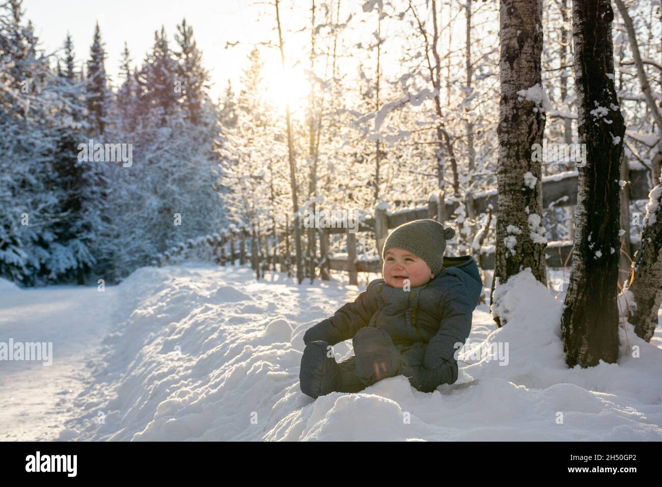 Happy baby in a snow suit smiling in the snow Stock Photo - Alamy