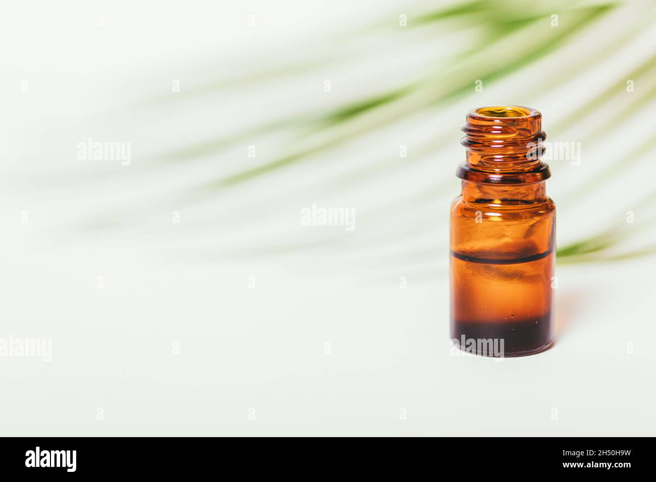 Aromatherapy essential oil, open dark glass bottle with liquid next to ...