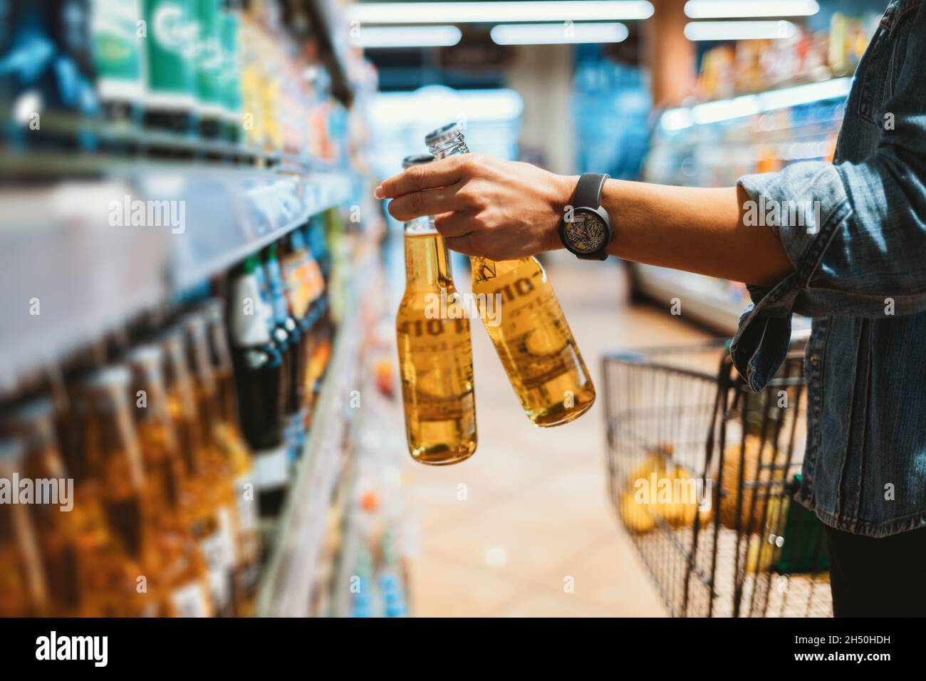 Close-up of female hand holding two glass bottle with alcoholic drink ...