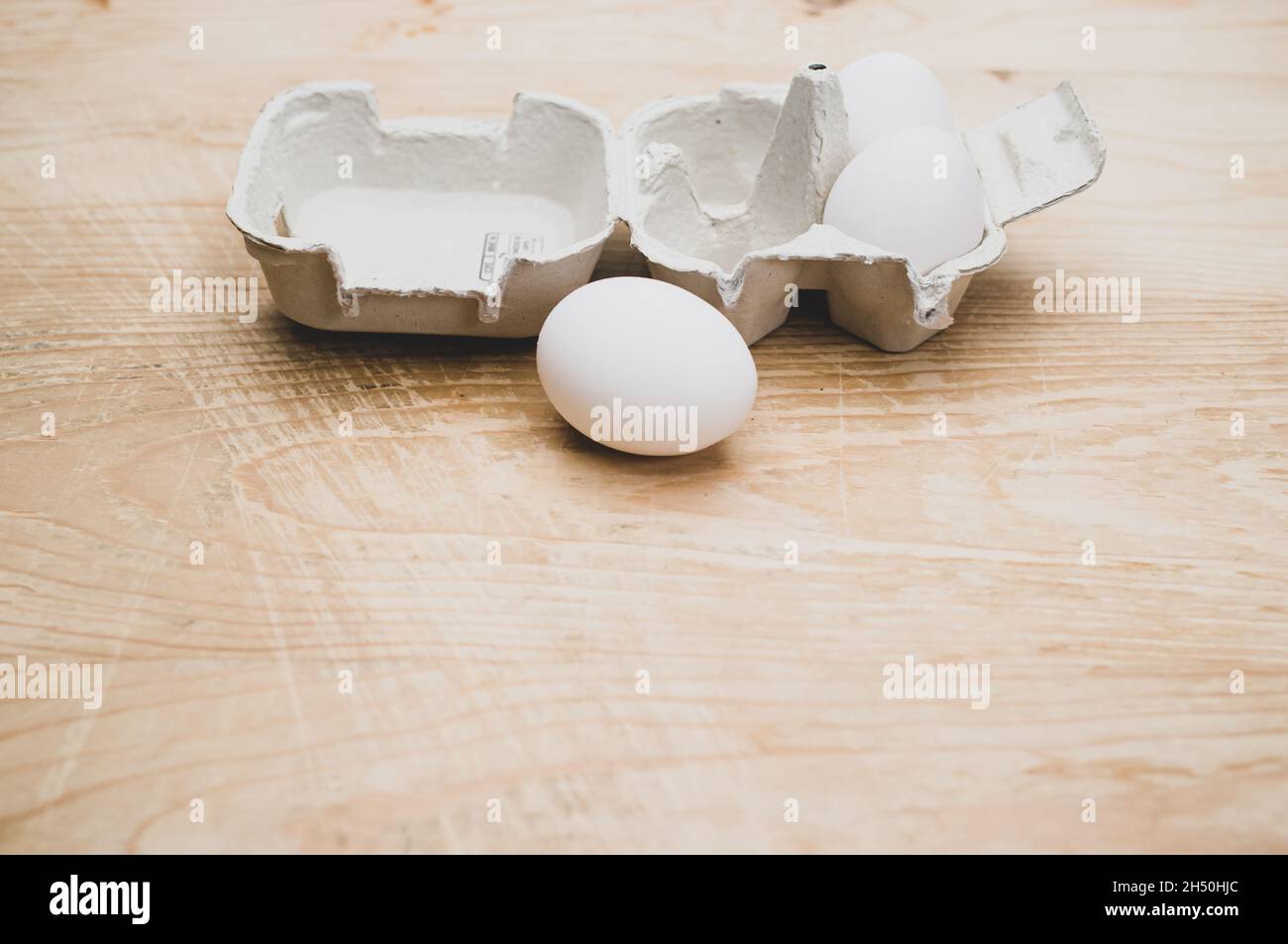 recycled cardboard egg box and white eggs on a rustic wooden background ...
