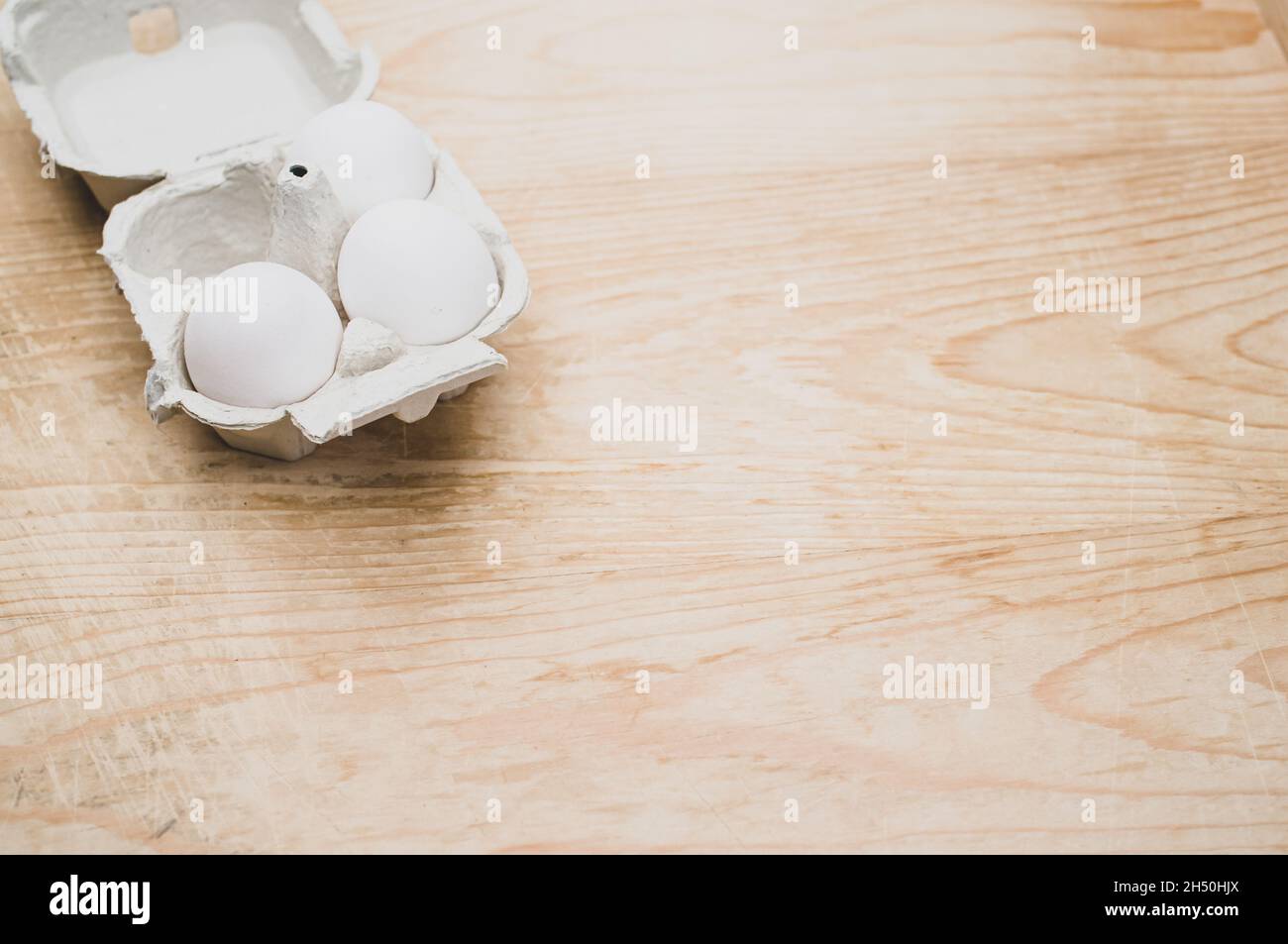 recycled cardboard egg box and white eggs on a rustic wooden background ...