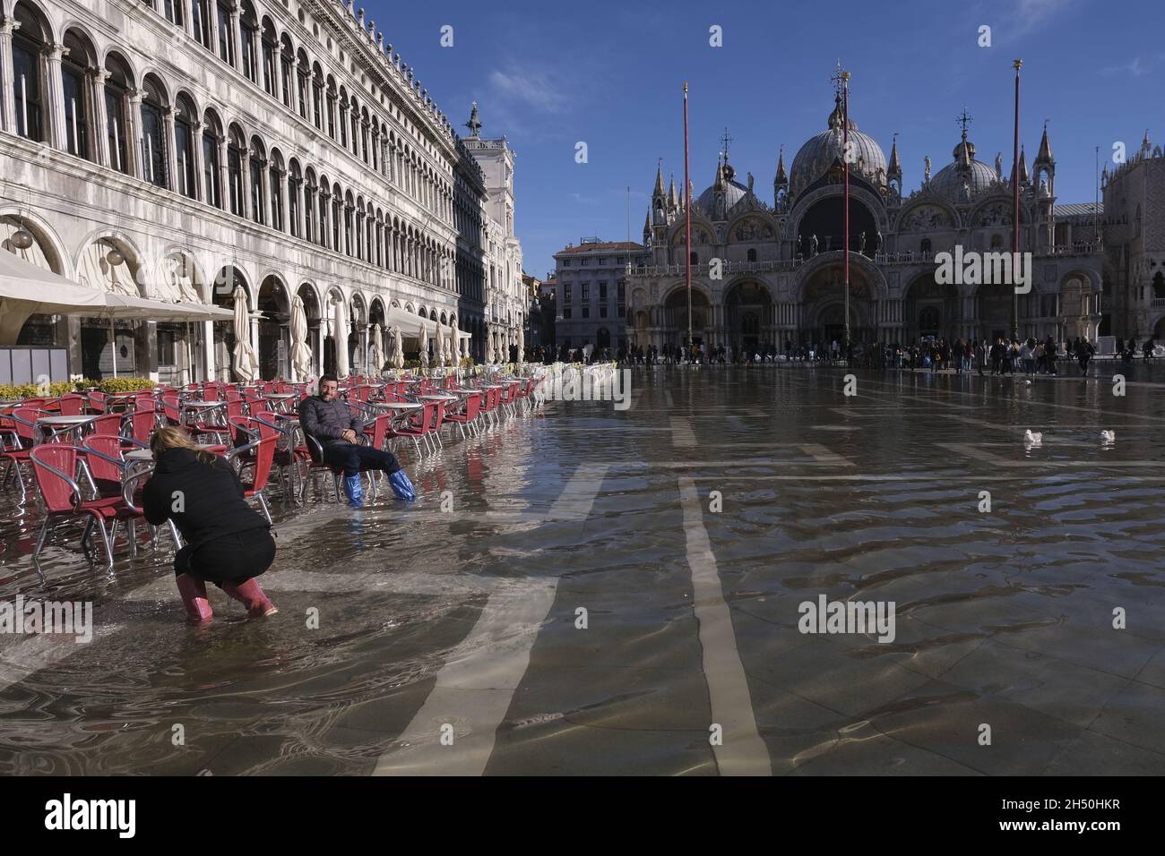 People walk in a flooded St. Mark's Square during seasonally high water ...