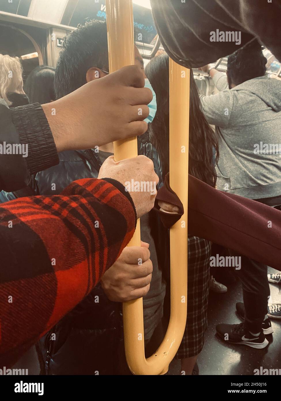 People hold on to the pole on a crowded , standing room only, subway ...