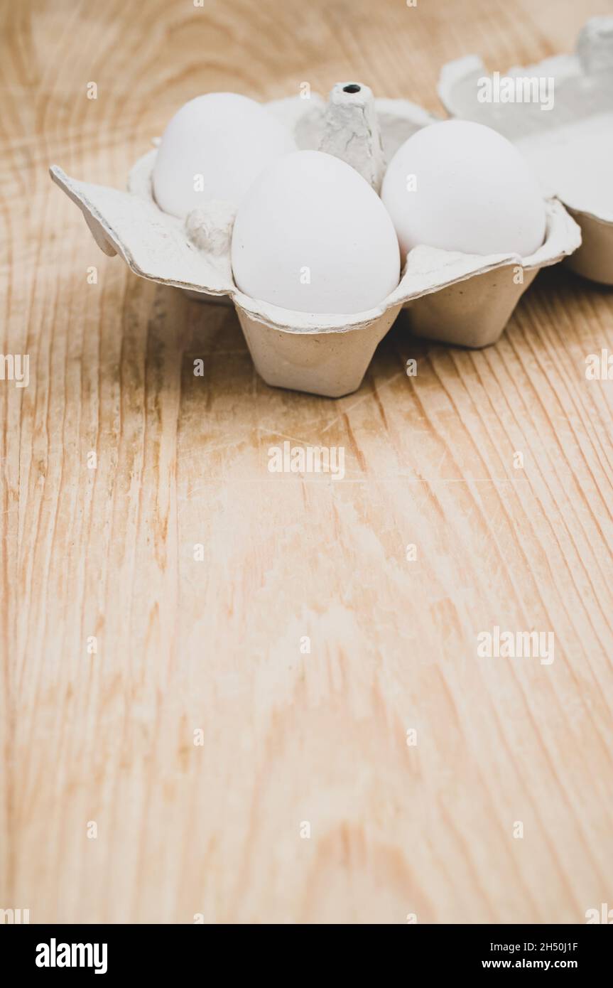 recycled cardboard egg box and white eggs on a rustic wooden background ...